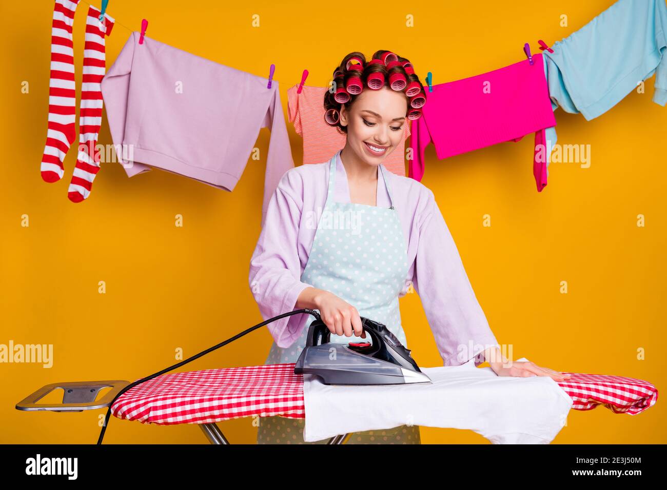 Portrait of pretty cheerful focused maid ironing things hygiene duty ...