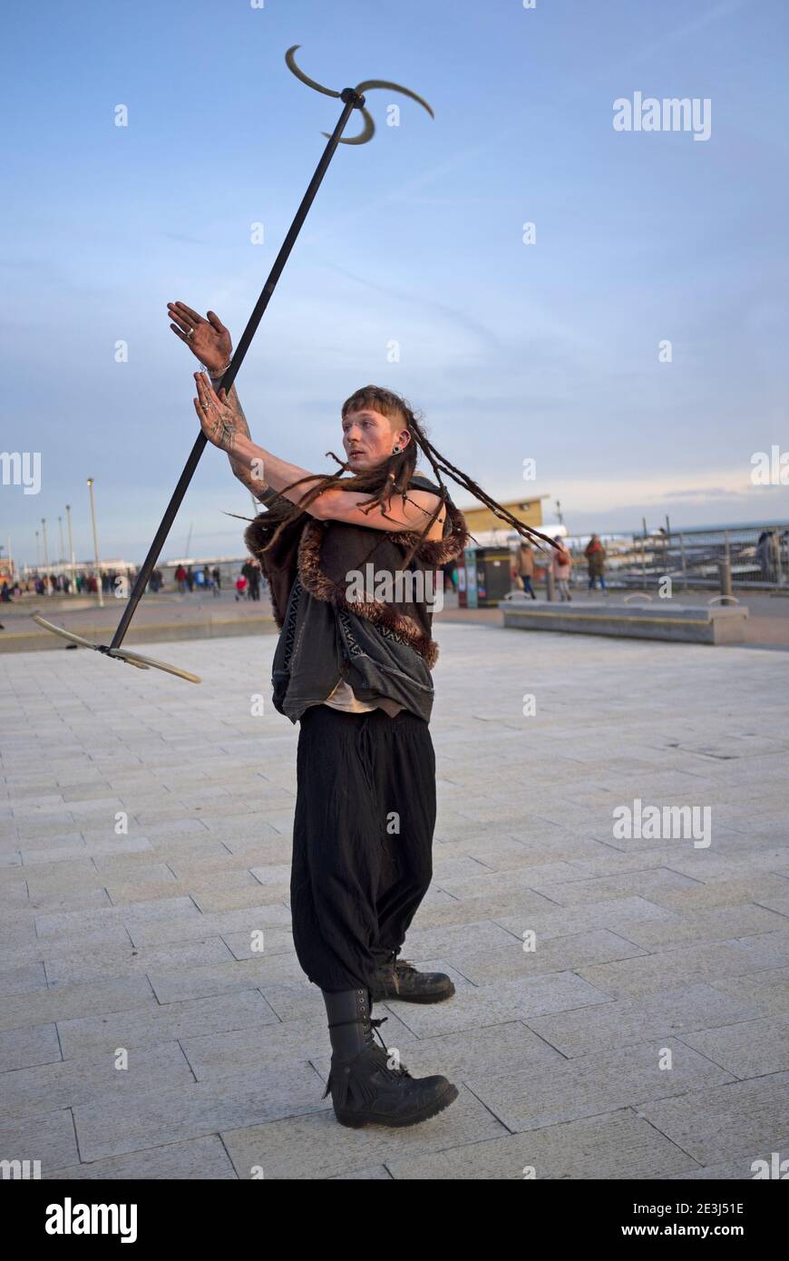 In Brighton a man practises his skills in in twirling a bladed stick ...