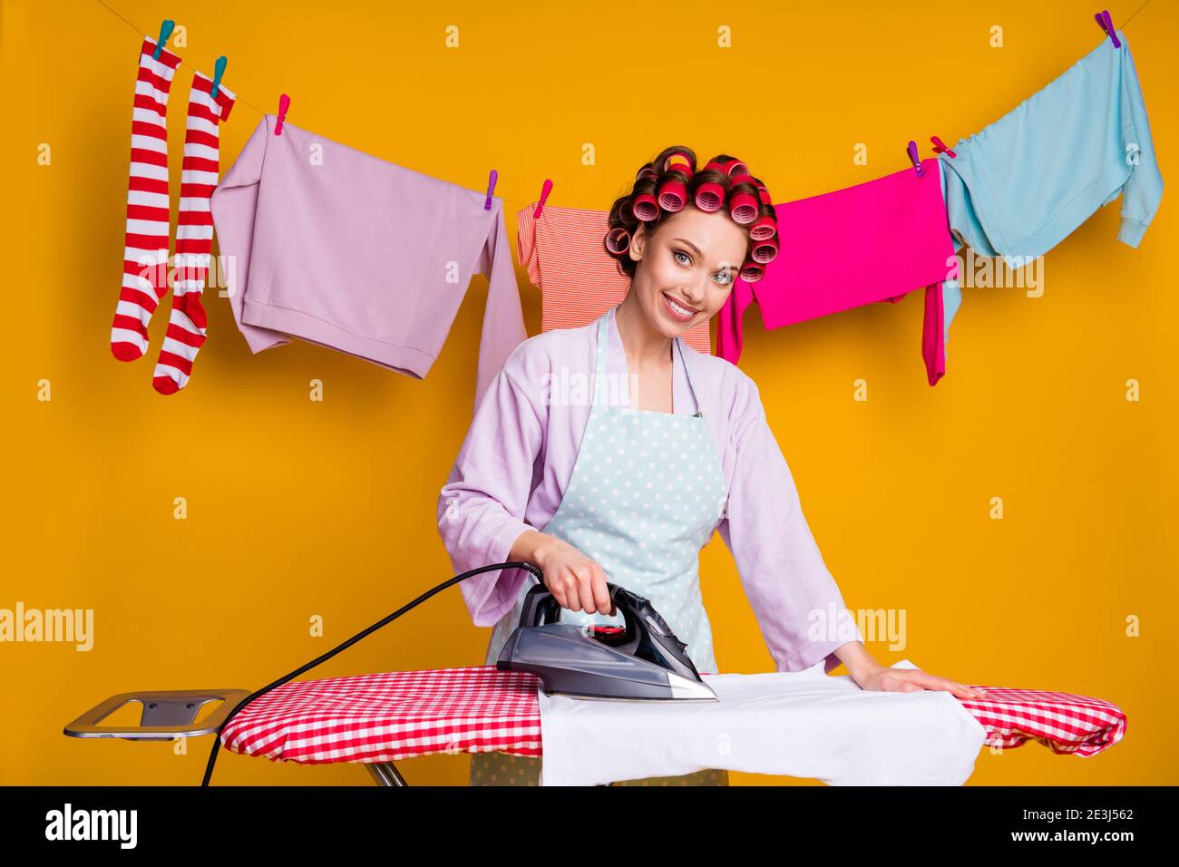 Portrait of attractive hardworking cheerful maid ironing things ...