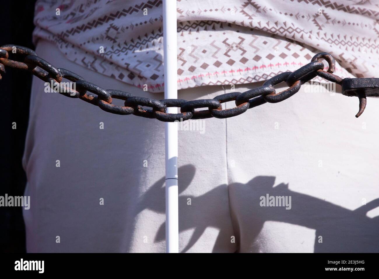 Blind woman standing behind a chain link barrier with her seeing cane ...