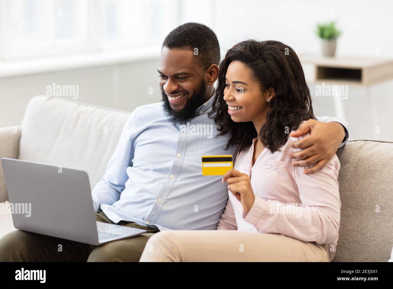 Black couple using computer and debit credit card at home Stock Photo ...
