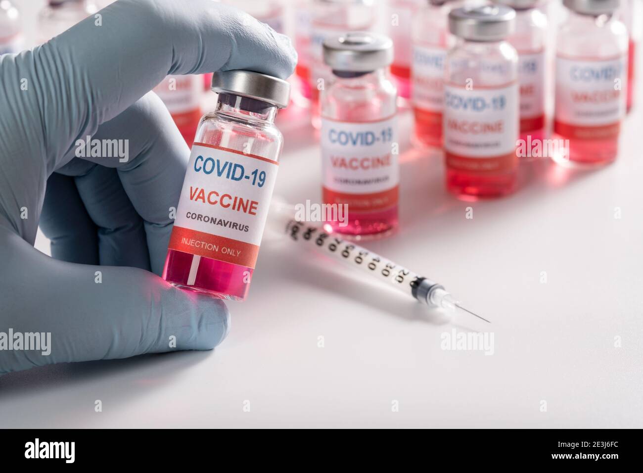 Vaccine vial in doctors hand closeup, syringe and many glass bottles ...