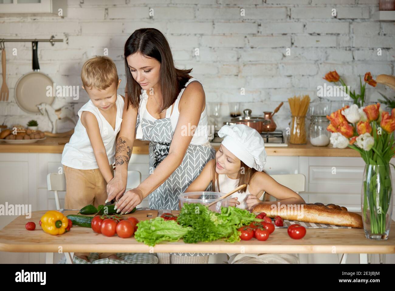 Mom cooks lunch with the kids. A woman teaches her daughter to cook ...
