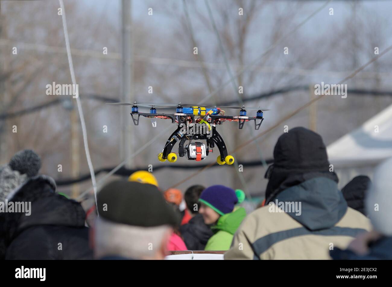 Handmade quadcopter with camera aboard flying over heads of crowd of ...