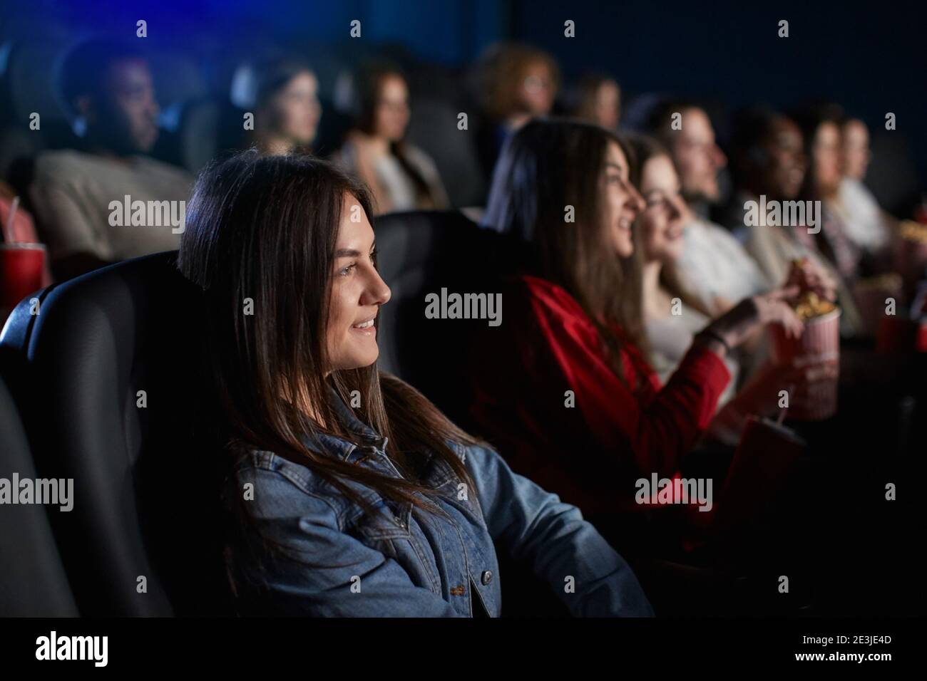 Side view of young stunning brunette girl watching movie in cinema ...