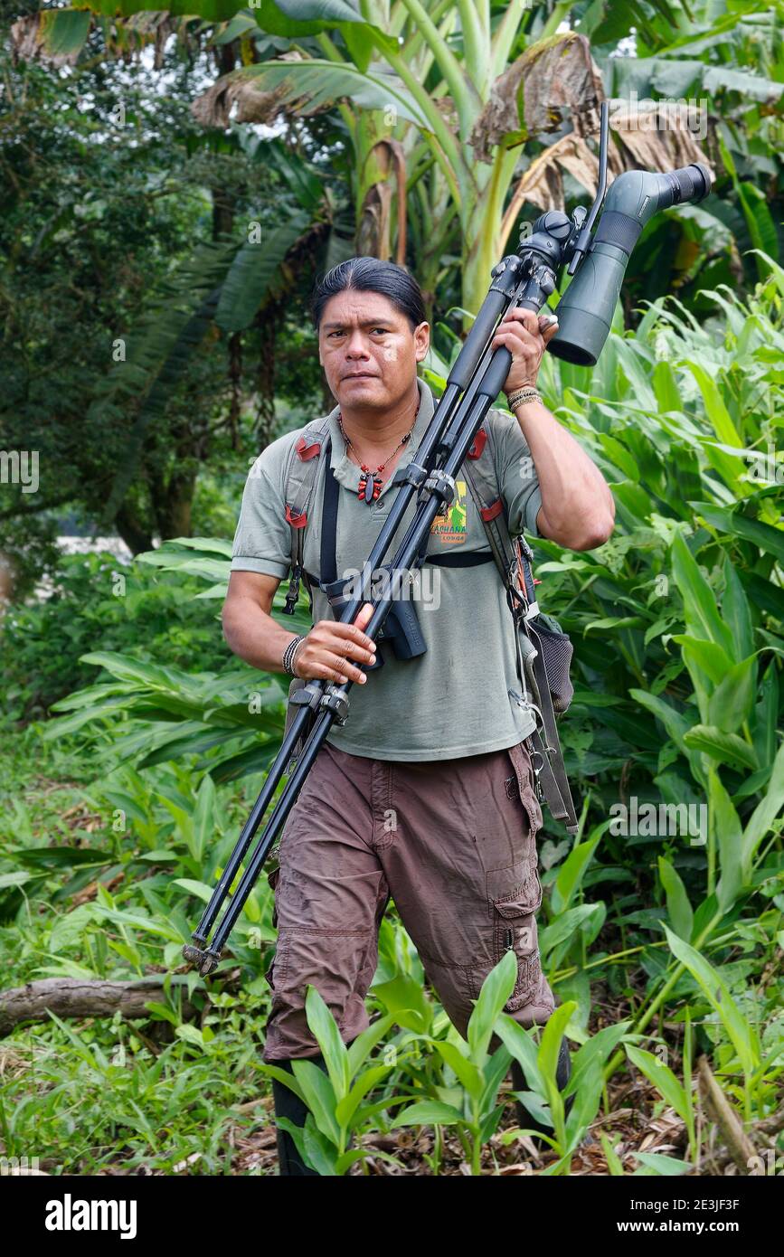 indigenous native man walking through vegetation, carrying large ...