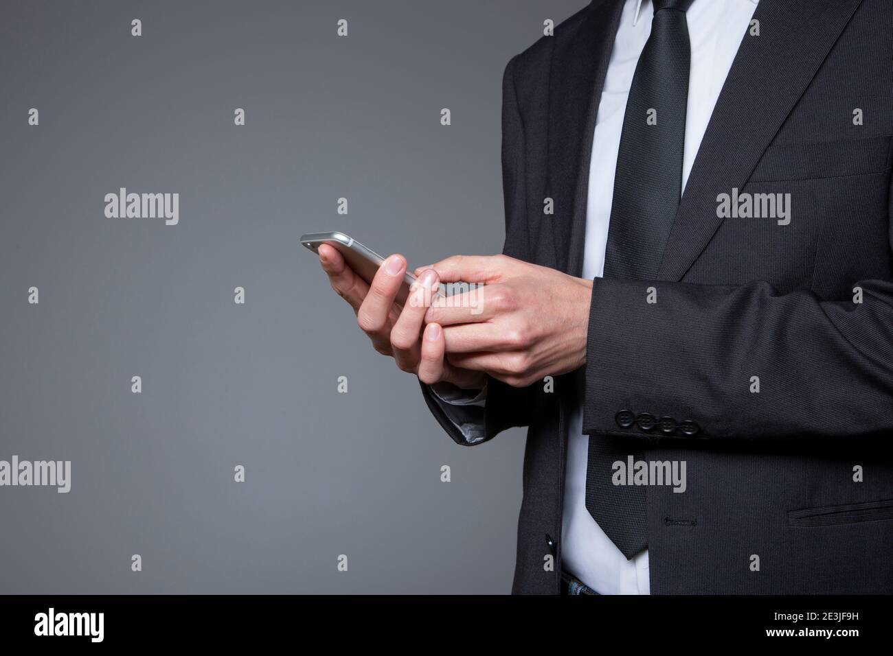 businessman wearing black suit using mobile phone Stock Photo - Alamy