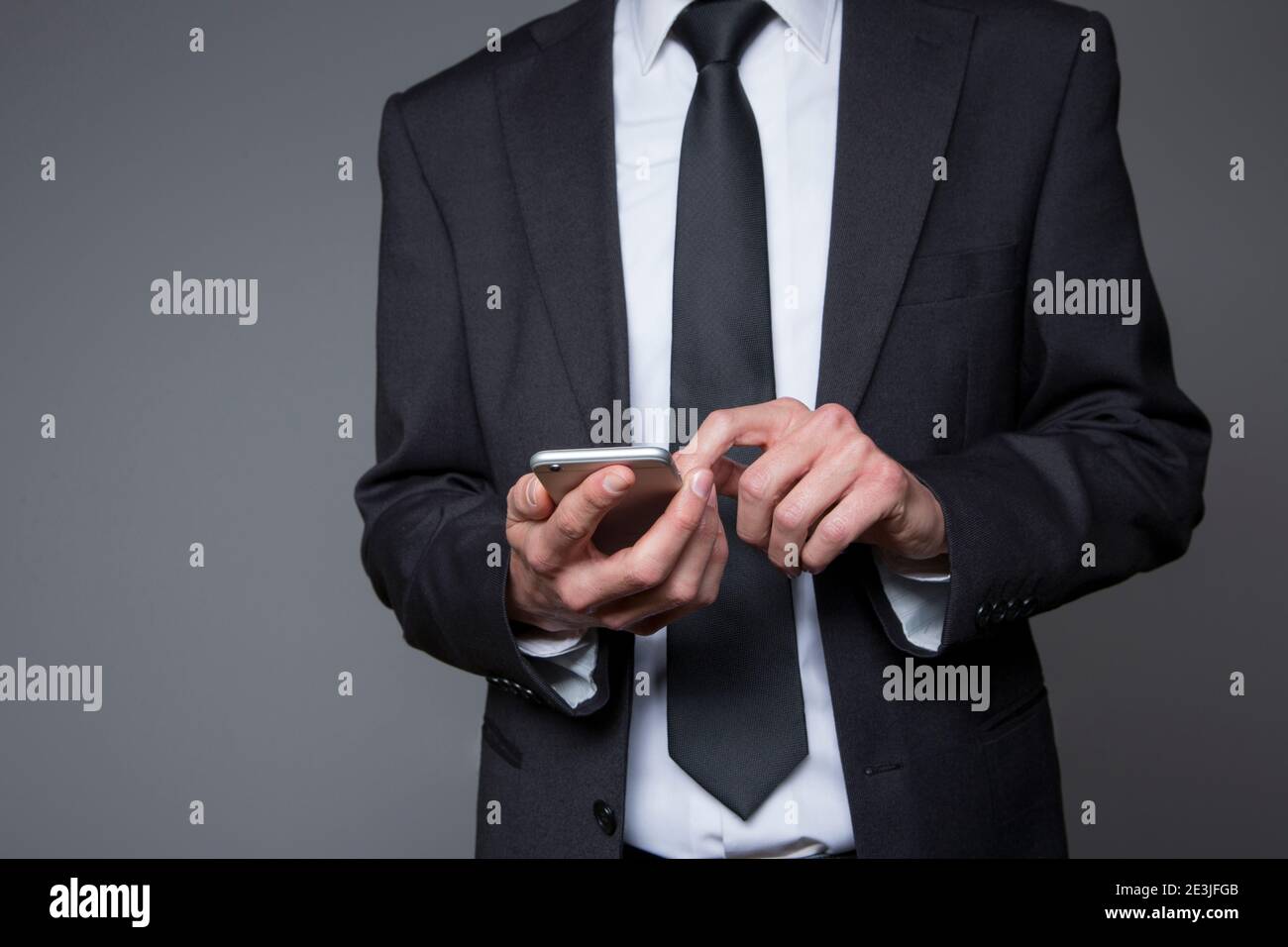 businessman wearing black suit using mobile phone Stock Photo - Alamy
