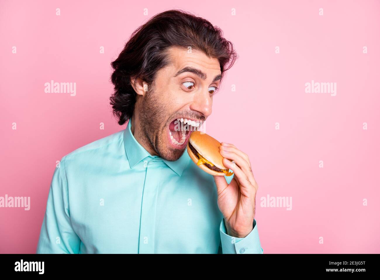 Photo portrait of guy biting cheeseburger isolated on pastel pink ...