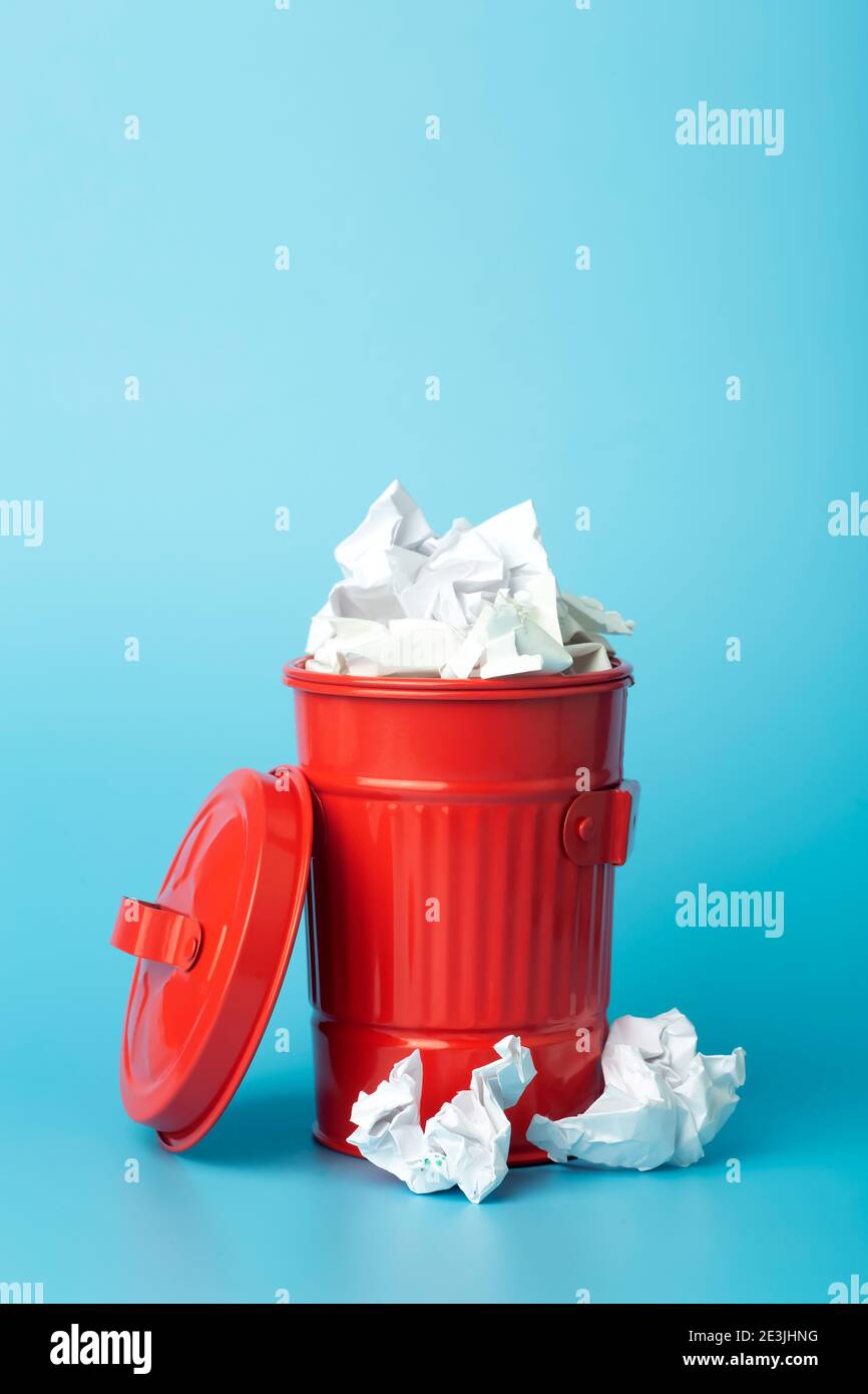 Paper trash and waste in a trash bin on a blue background. Waste and ...