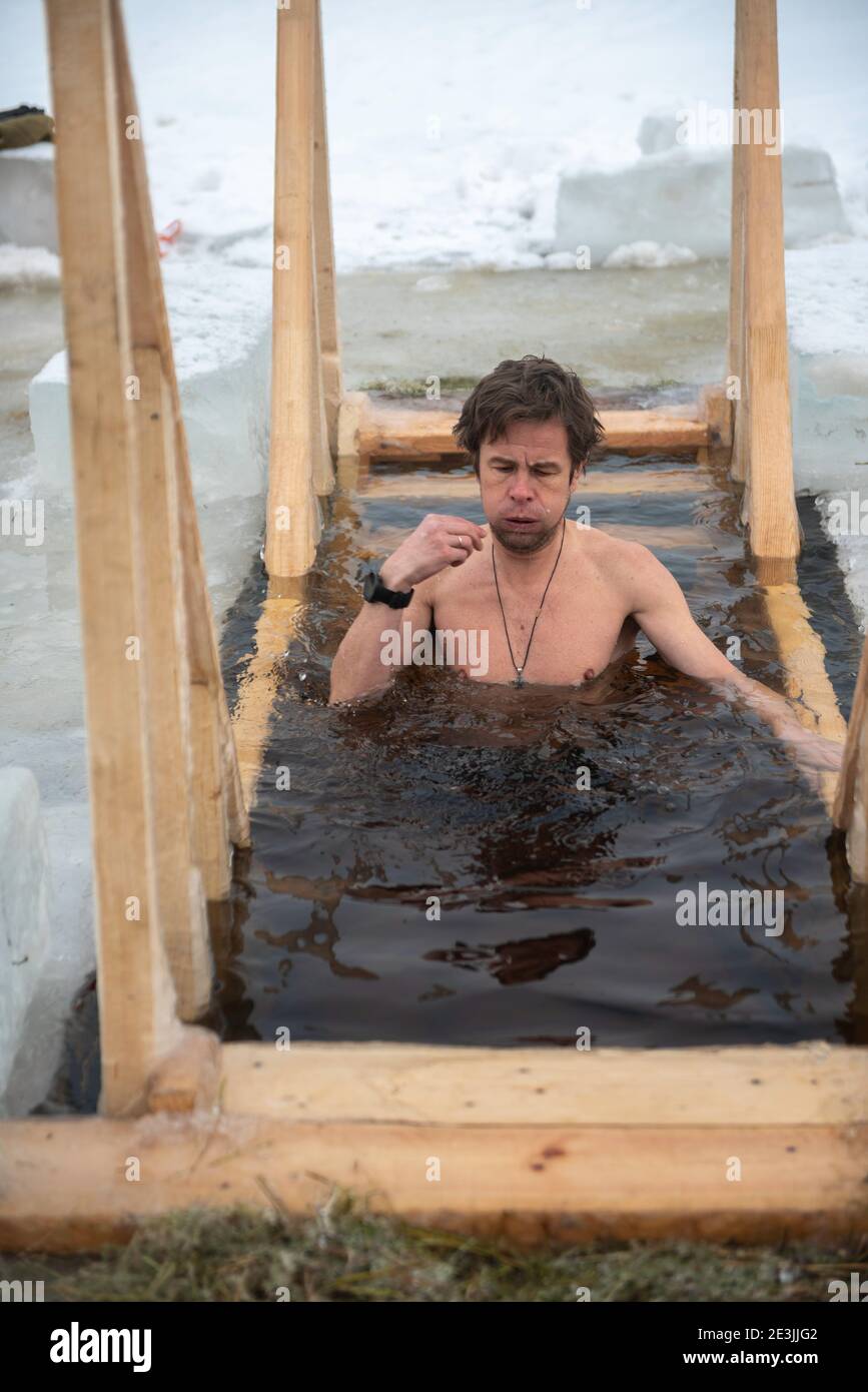 Man bathes into cold water of ice-hole on Epiphany day in Neva River ...