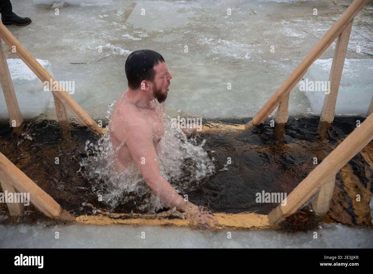Man bathes into cold water of ice-hole on Epiphany day in Neva River ...
