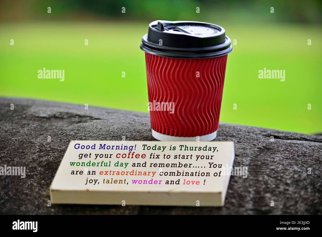 Red paper cup of coffee with text written on chalkboard and greenery ...