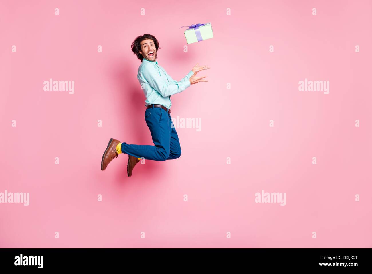 Full length photo portrait of guy catching gift box jumping up isolated ...
