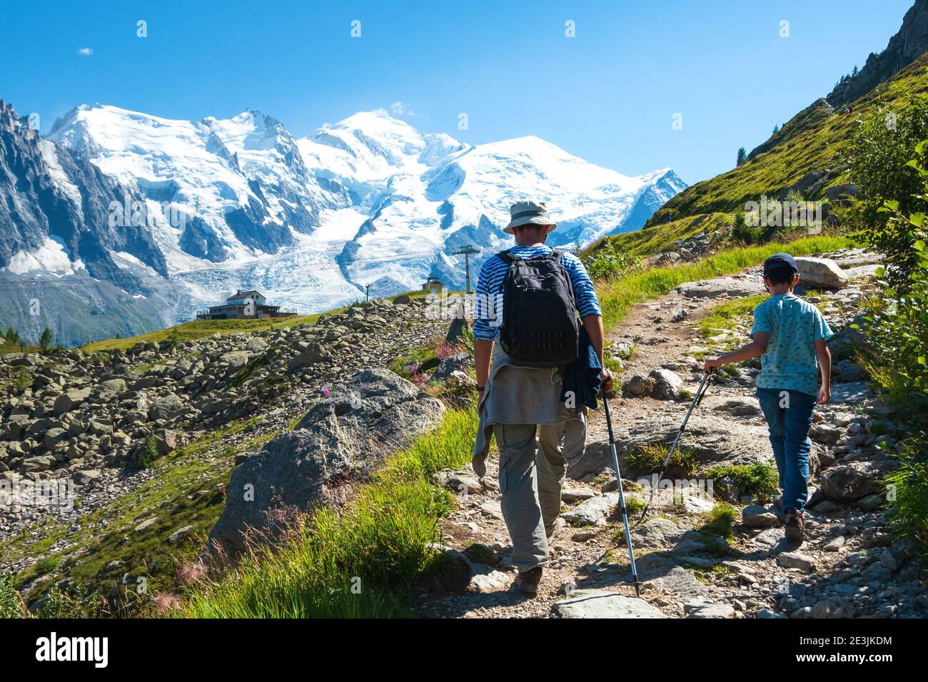 Father and son hiking in French Alps in summer. Back view. Snow covered ...
