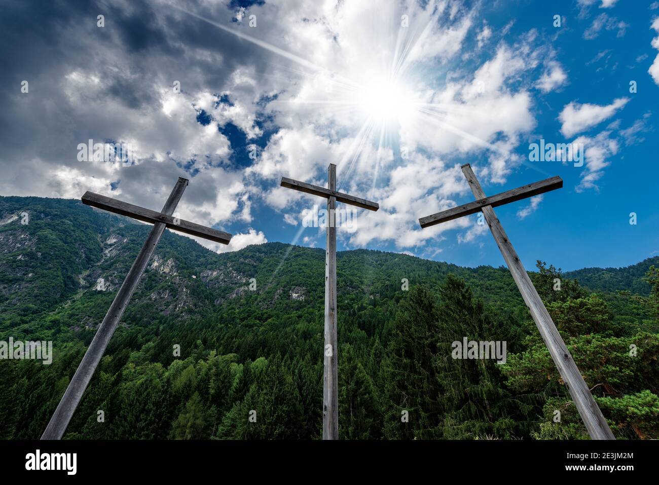 Three religious crosses in mountain with blue sky, clouds and sun rays ...
