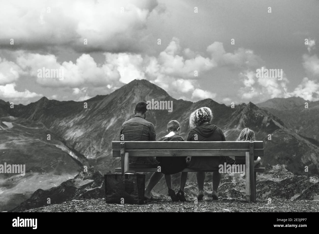 Family resting on bench in Alps, France with beautiful mountain view ...
