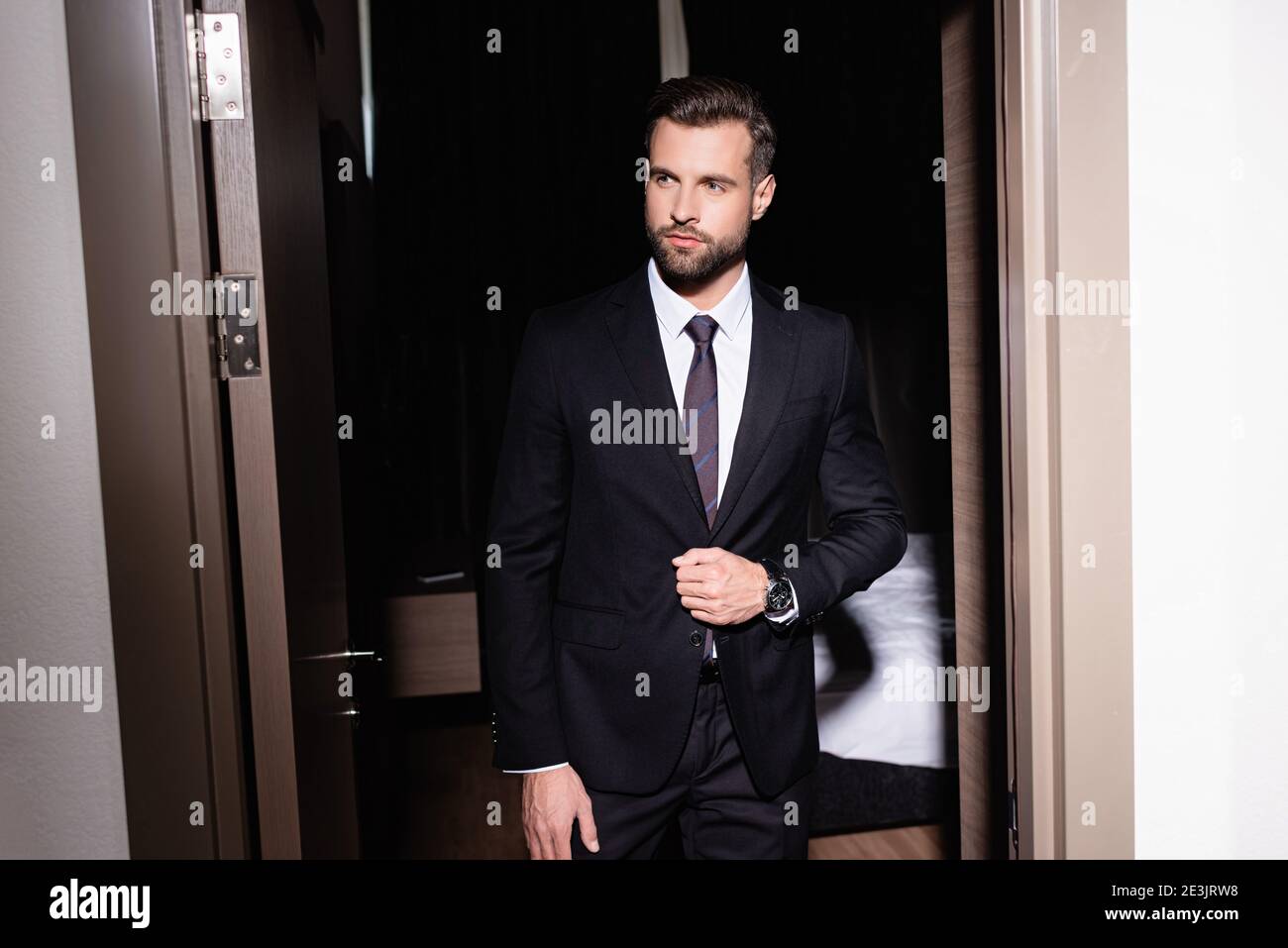 Man in formal wear adjusting jacket in hotel during night Stock Photo ...