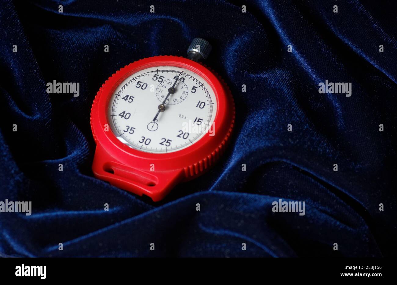 Red stopwatch clock on blue velvet holds, closeup, copy space, 80s ...