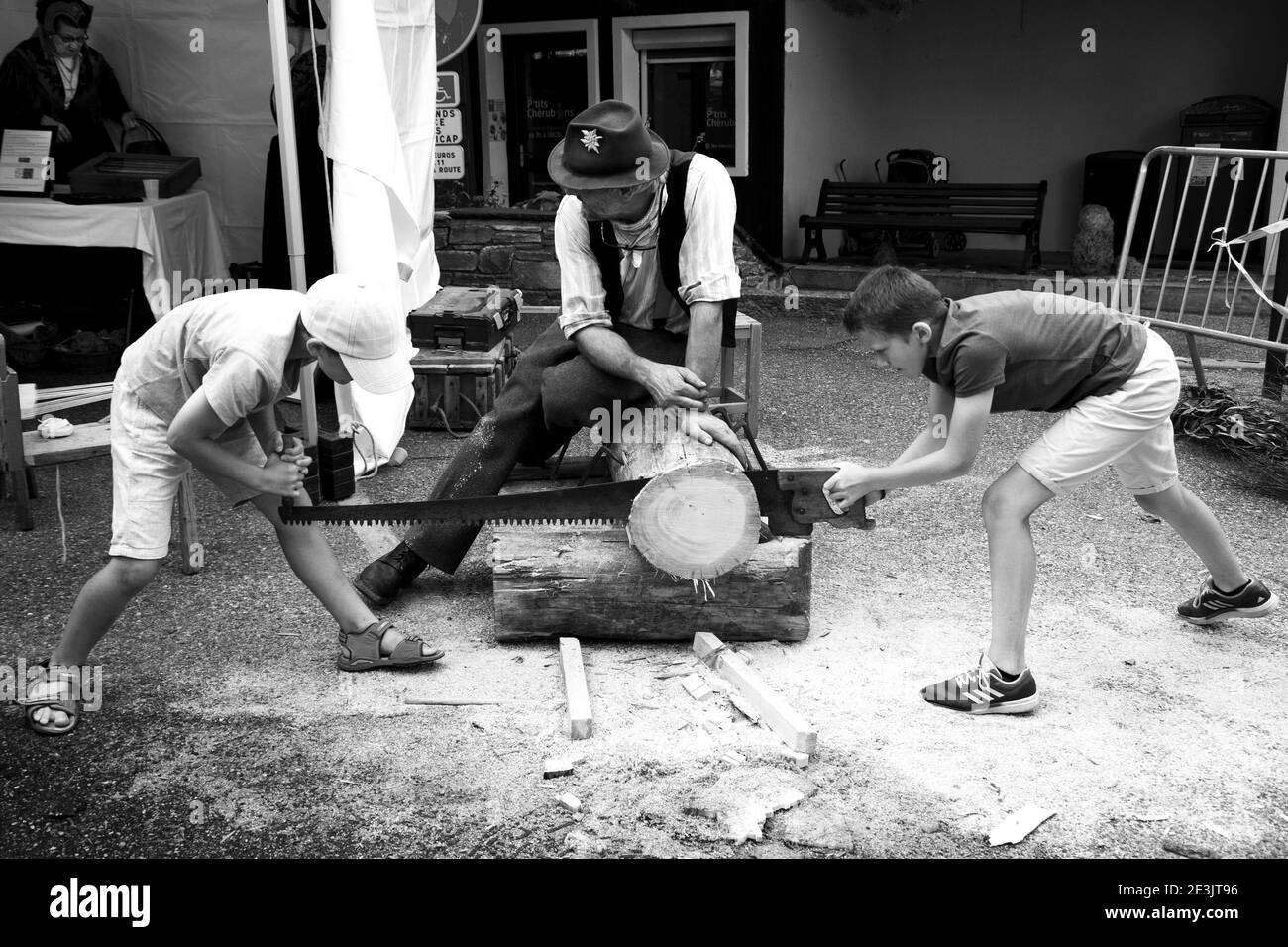 BOURG-SAINT-MAURICE, FRANCE - AUGUST 19, 2018: Boys trying to saw a log ...
