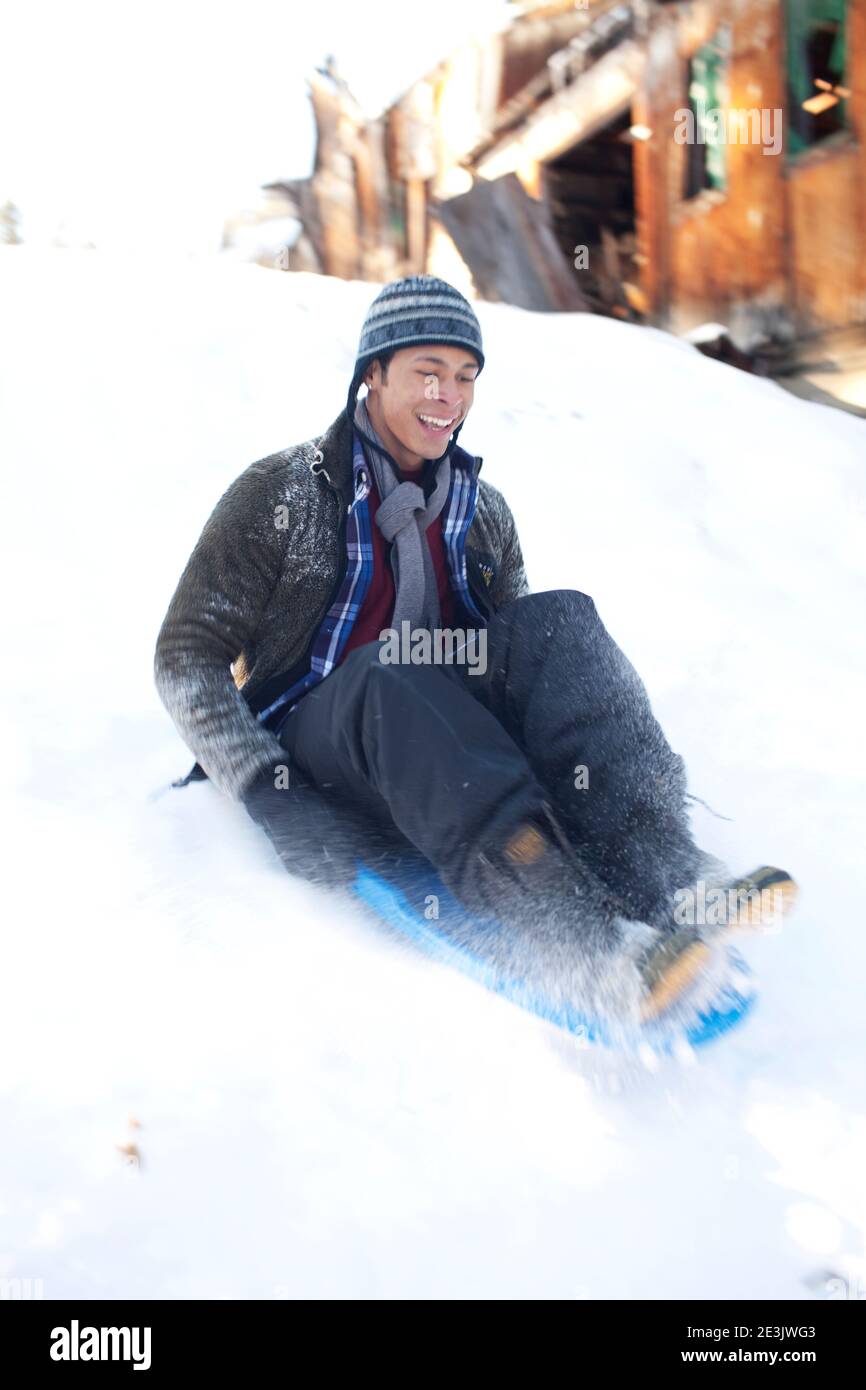 Man sliding down snowy hill in sled Stock Photo - Alamy