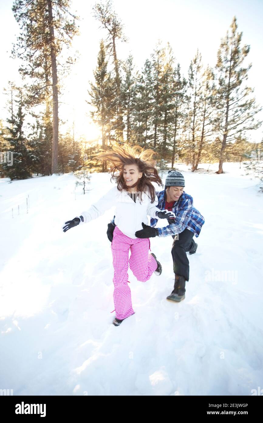 Man playfully chasing woman in snowy forest Stock Photo - Alamy