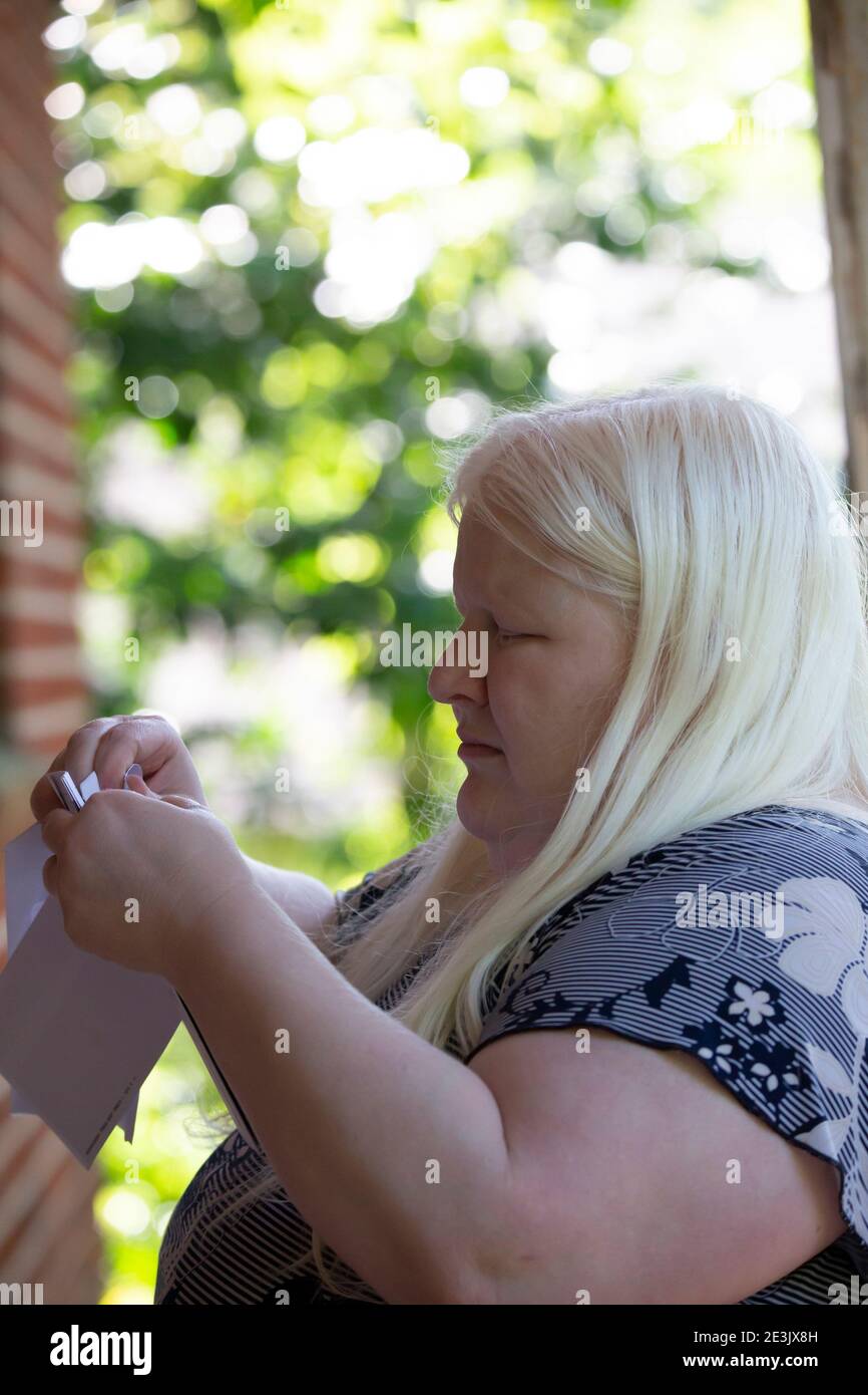 Woman opening mail outside of a red brick house Stock Photo - Alamy