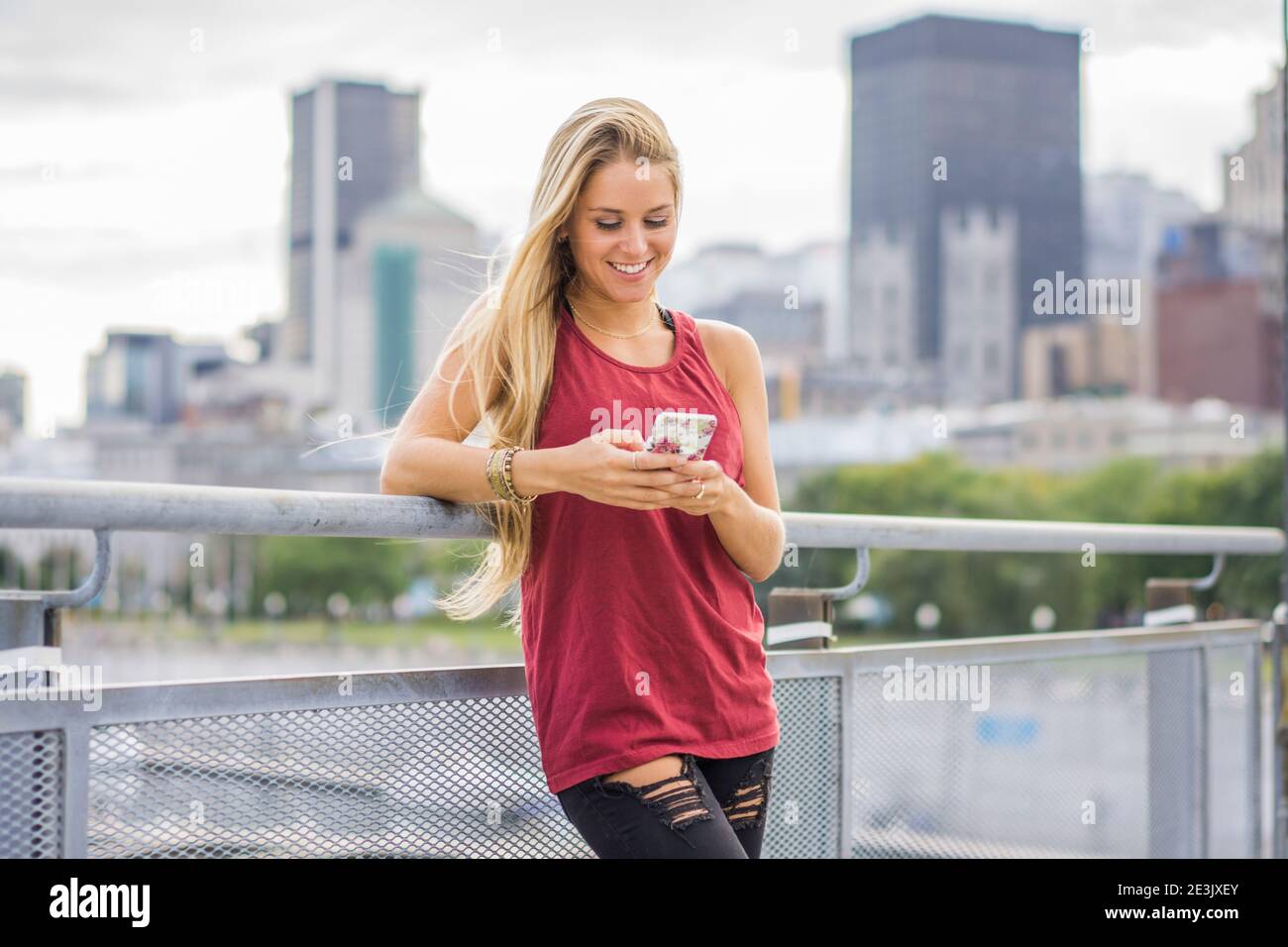 Female millennial using smartphone with city behind, Montreal, Quebec ...