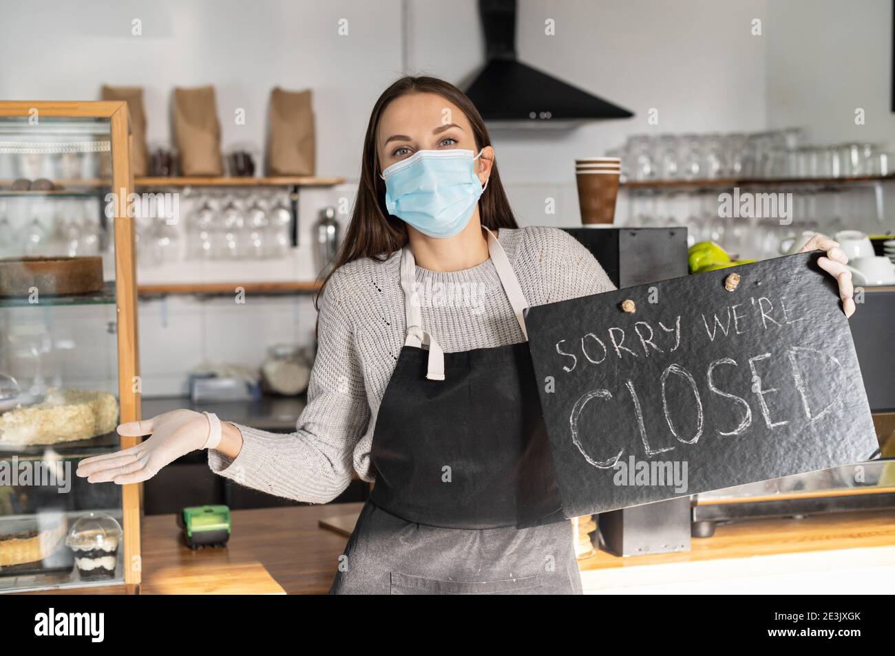 A waitress in a medical mask with closed sign Stock Photo - Alamy