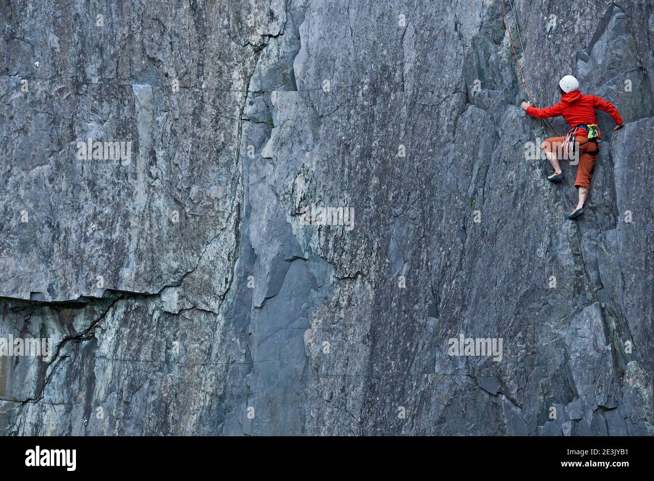 woman climbing up steep rock face at Slate quarry in North Wales Stock ...