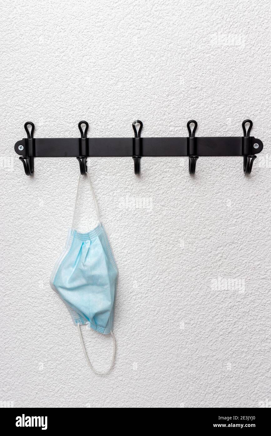 Surgical hygiene mask hanging from a hook in wardrobe. Concept of ...