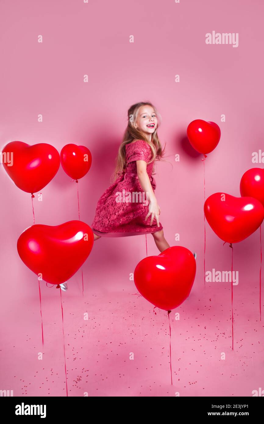 Valentines day. Little cute girl jumping with red heart balloons on ...