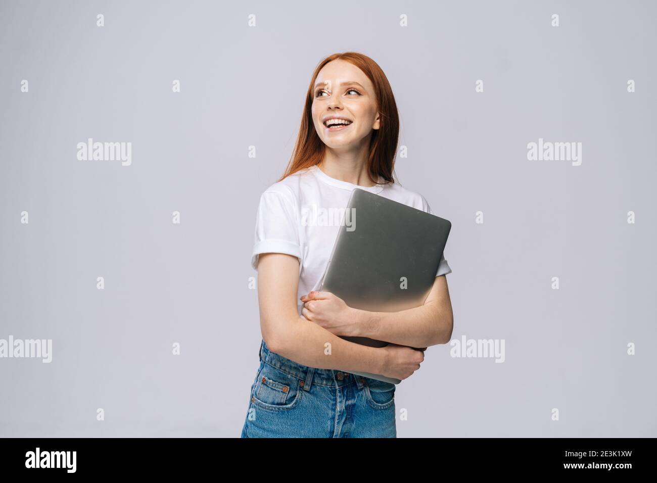 Happy young woman student holding laptop computer and looking away on ...