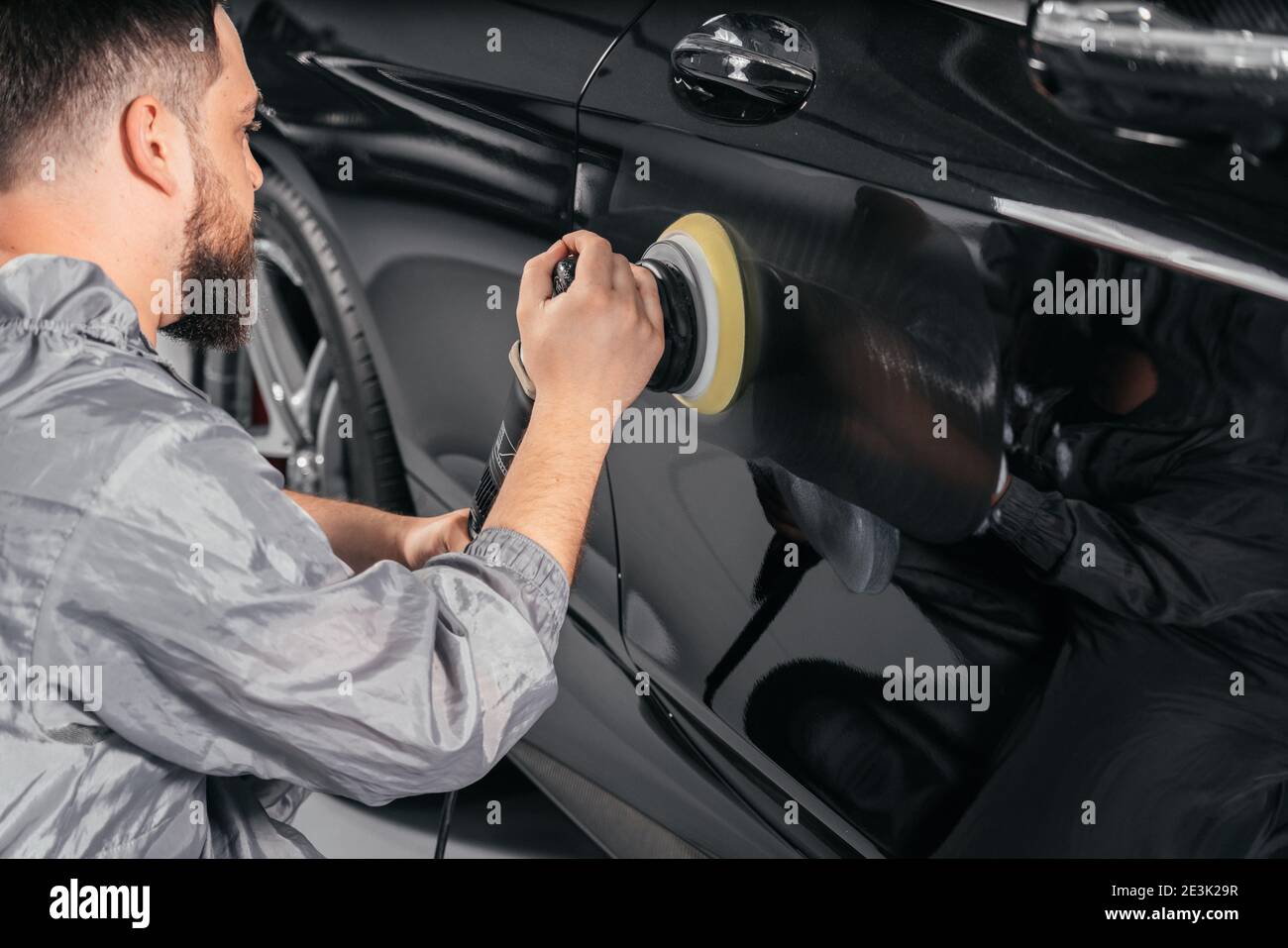 Worker polishing car with special grinder and wax from scratches at the ...