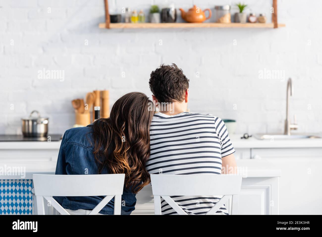 back view of woman and man sitting on chairs in kitchen Stock Photo - Alamy