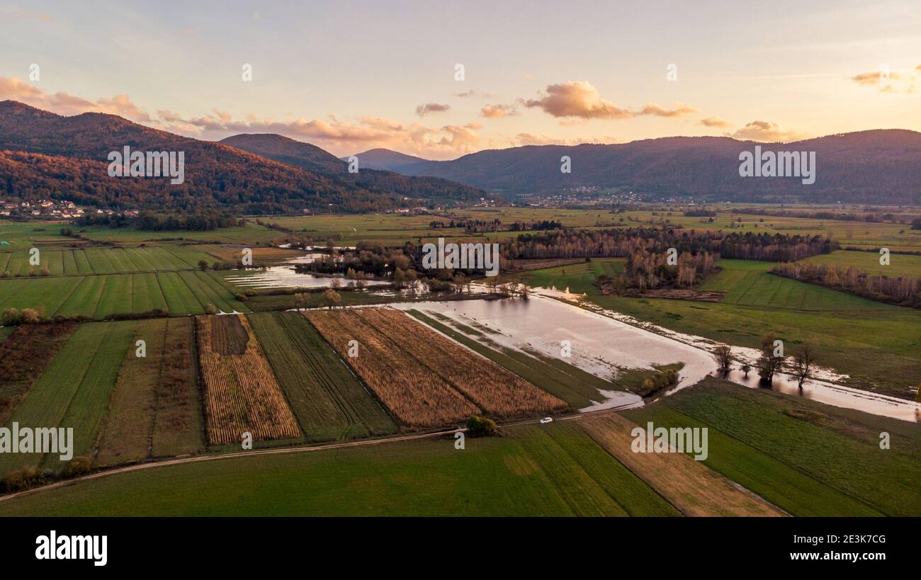 Spectacular aerial panorama of river flowing through fields at sunset ...