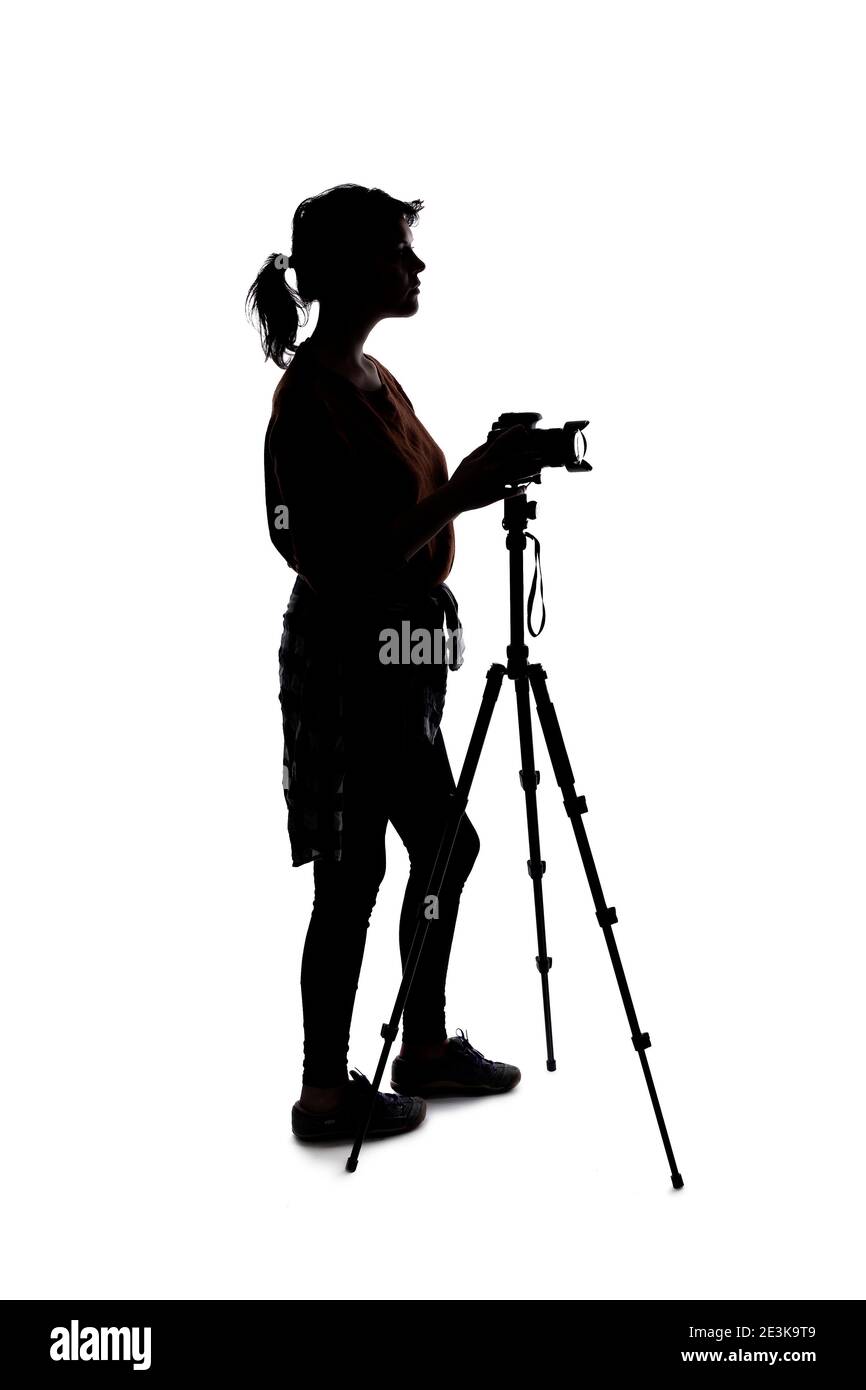 Backlit silhouette of a female photographer hiking and isolated on a ...