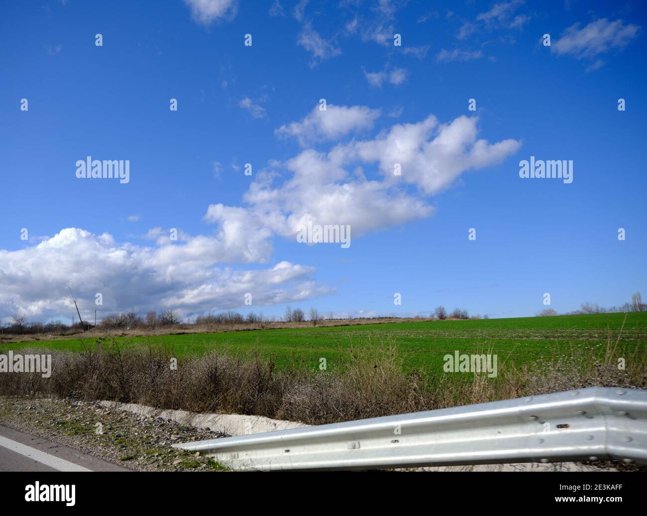 Very green grass near the road and highway with huge clouds and ...