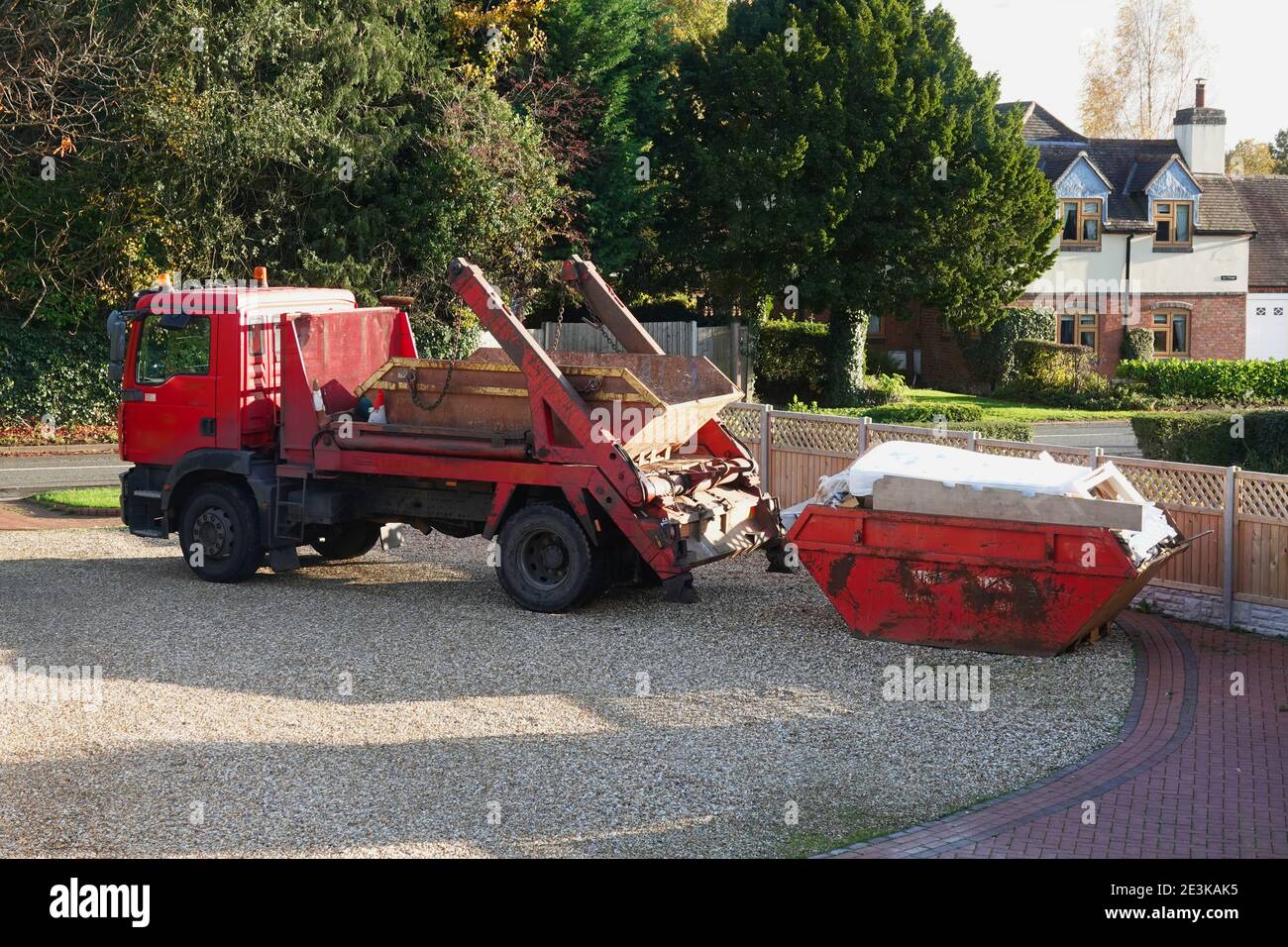 A skip lorry collecting a full skip form a house in an urban road Stock ...