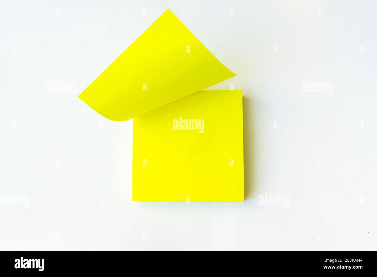 A square blank yellow note on white wall. Yellow reminder note Stock ...