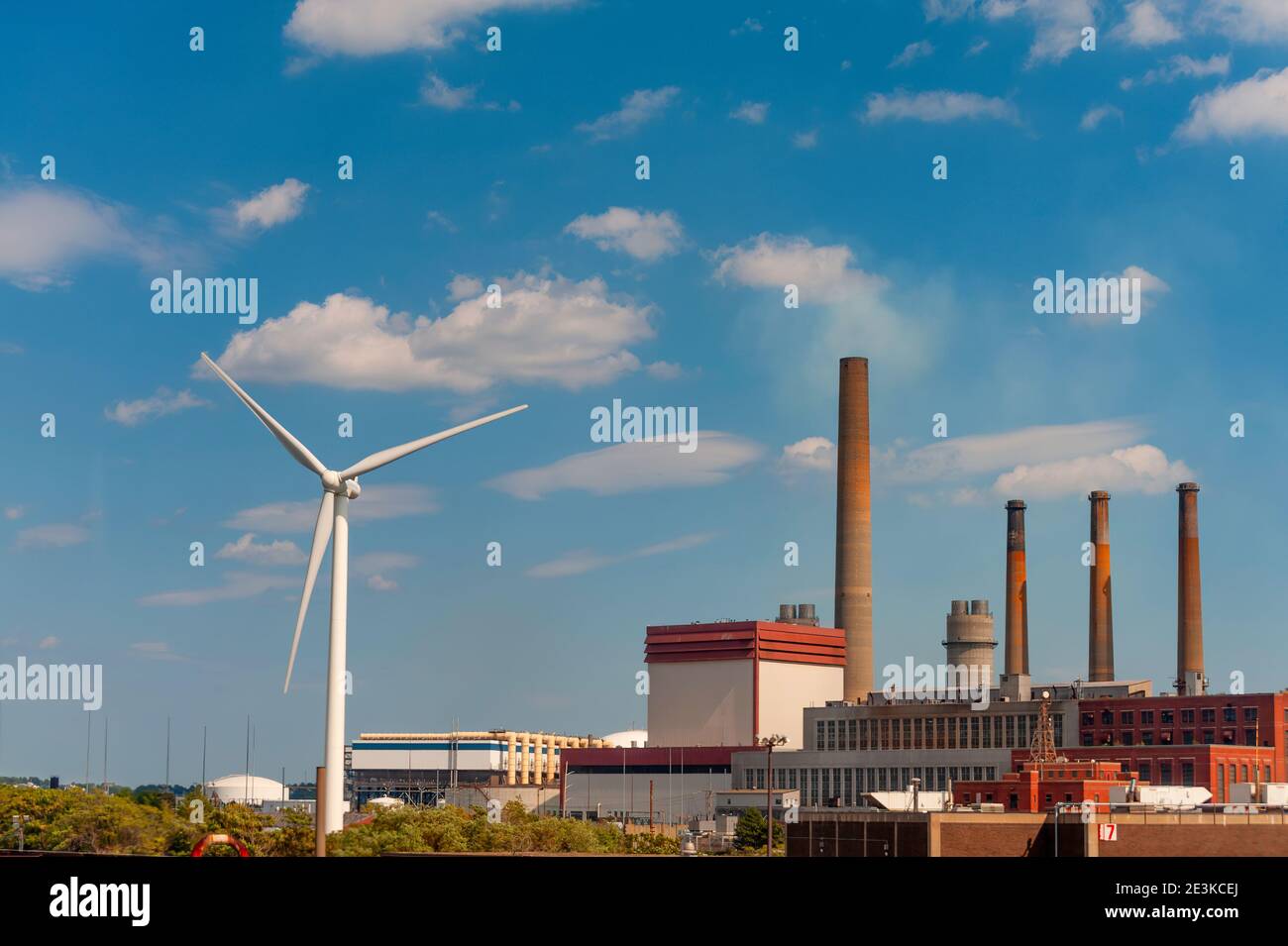 A wind turbine and factory are seen from a window of a moving train ...
