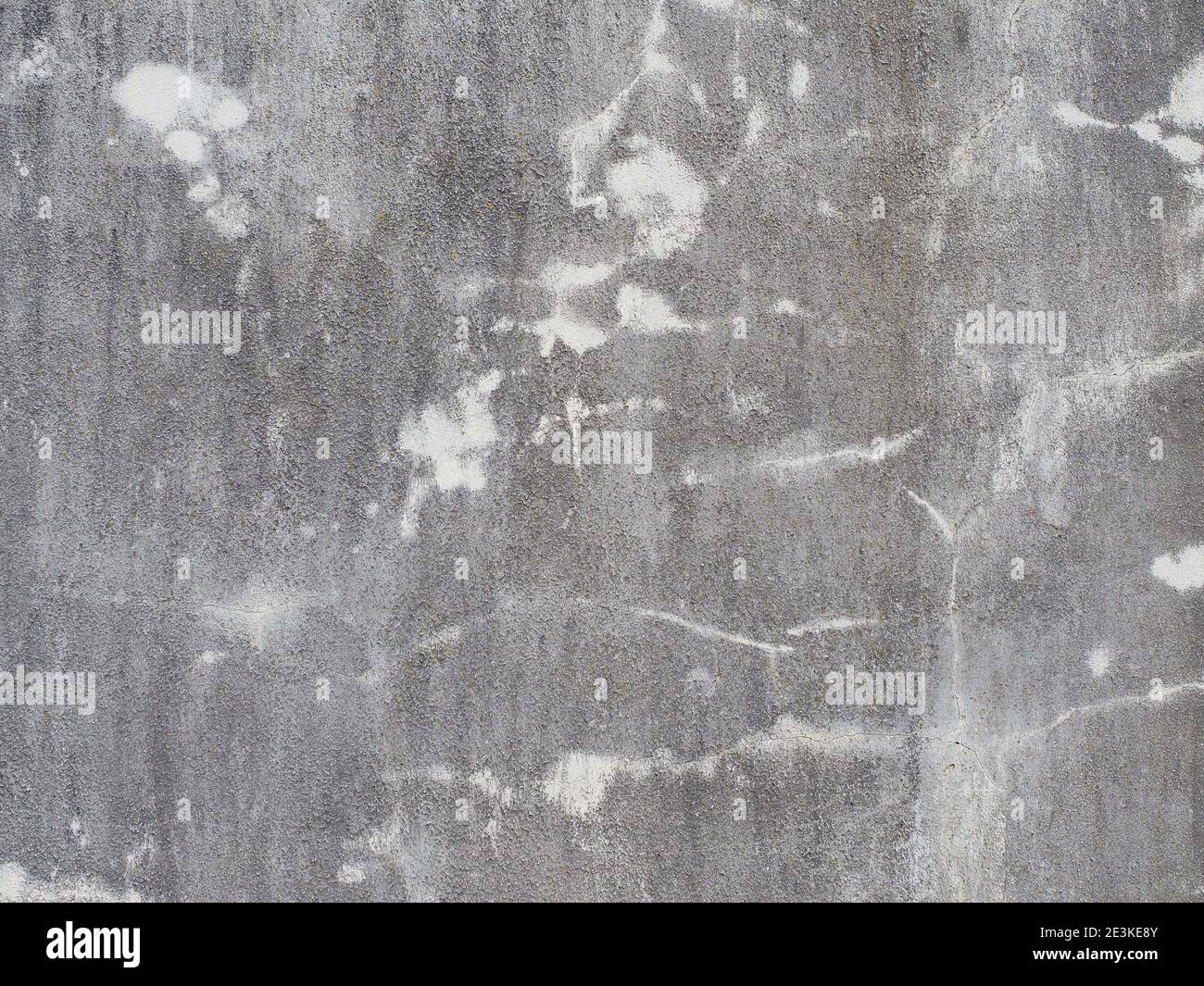 A wall with rough gray plaster and light spots on it. Full screen photo ...