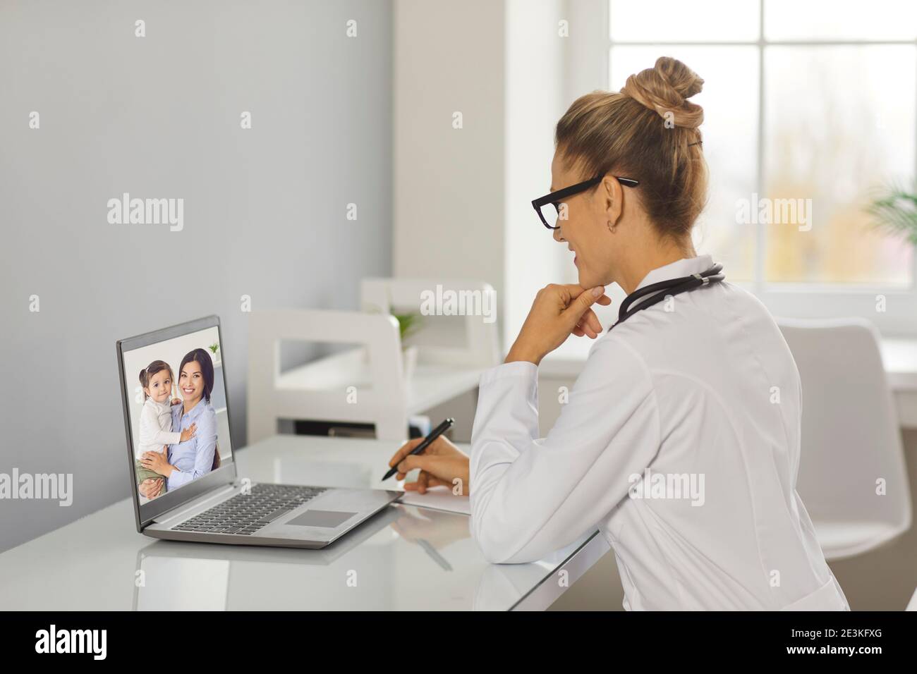 Female family doctor giving an online consultation to a mother with her ...