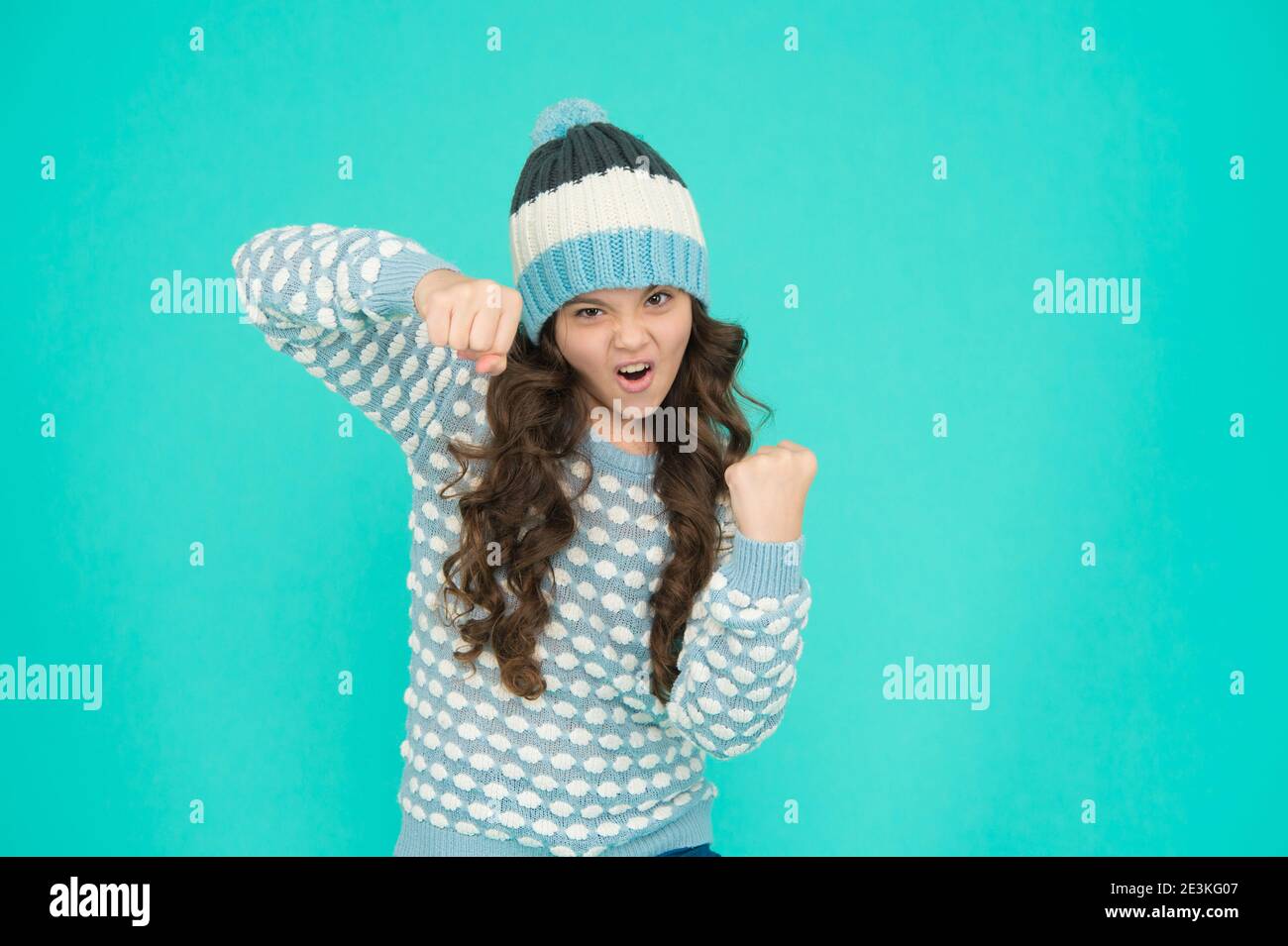 angry kid girl punching and warming up in winter knitted hat and ...