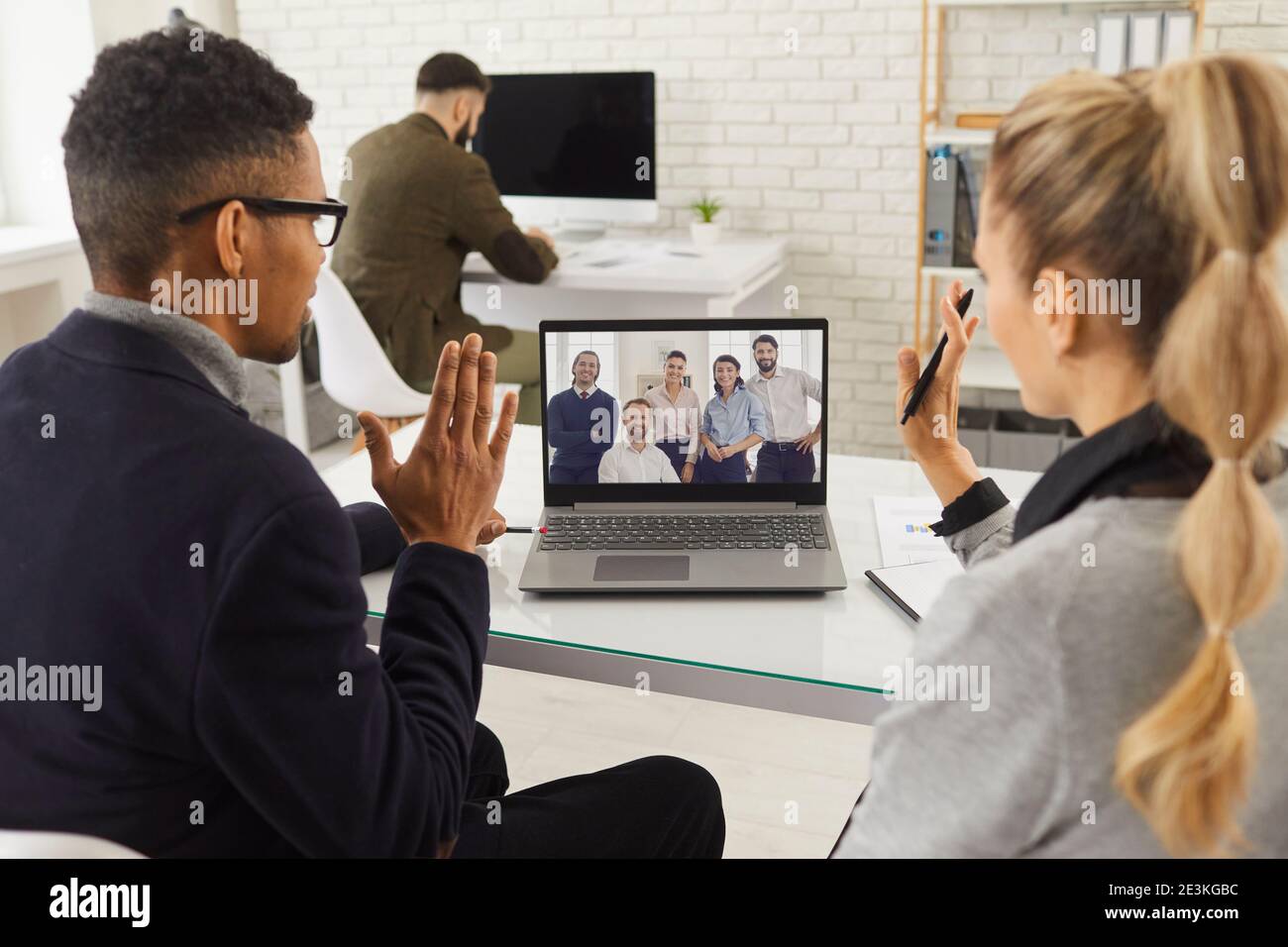 Young diverse business people waving hands to their coworkers during ...