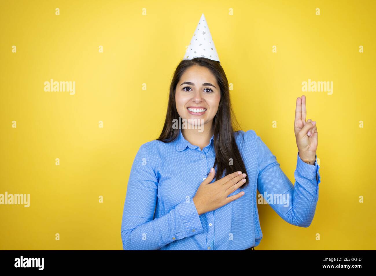 Young caucasian woman wearing a birthday hat over isolated yellow ...