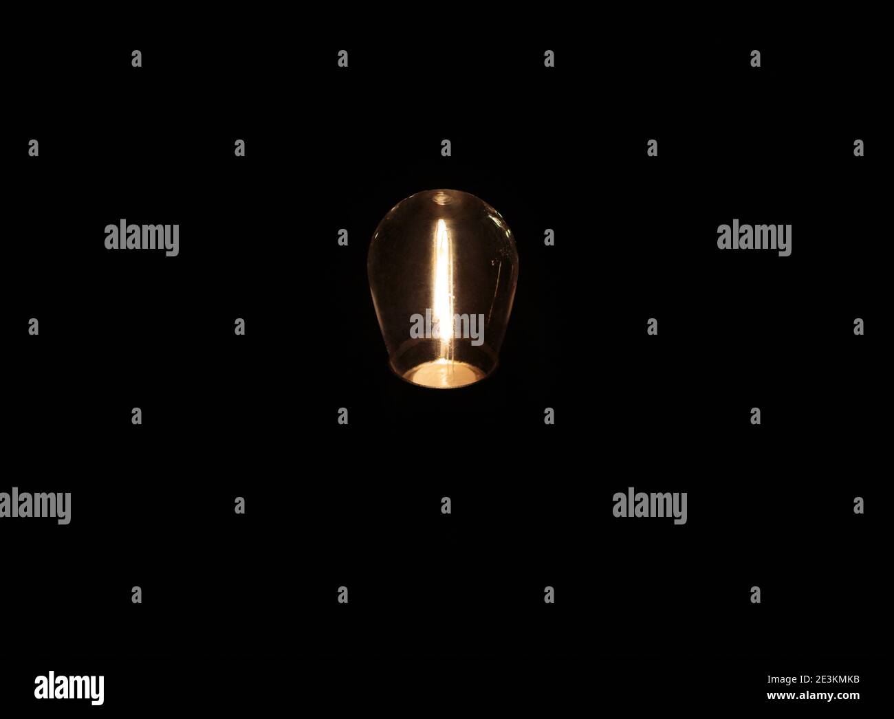 an illuminated edison light bulb on a black background Stock Photo - Alamy