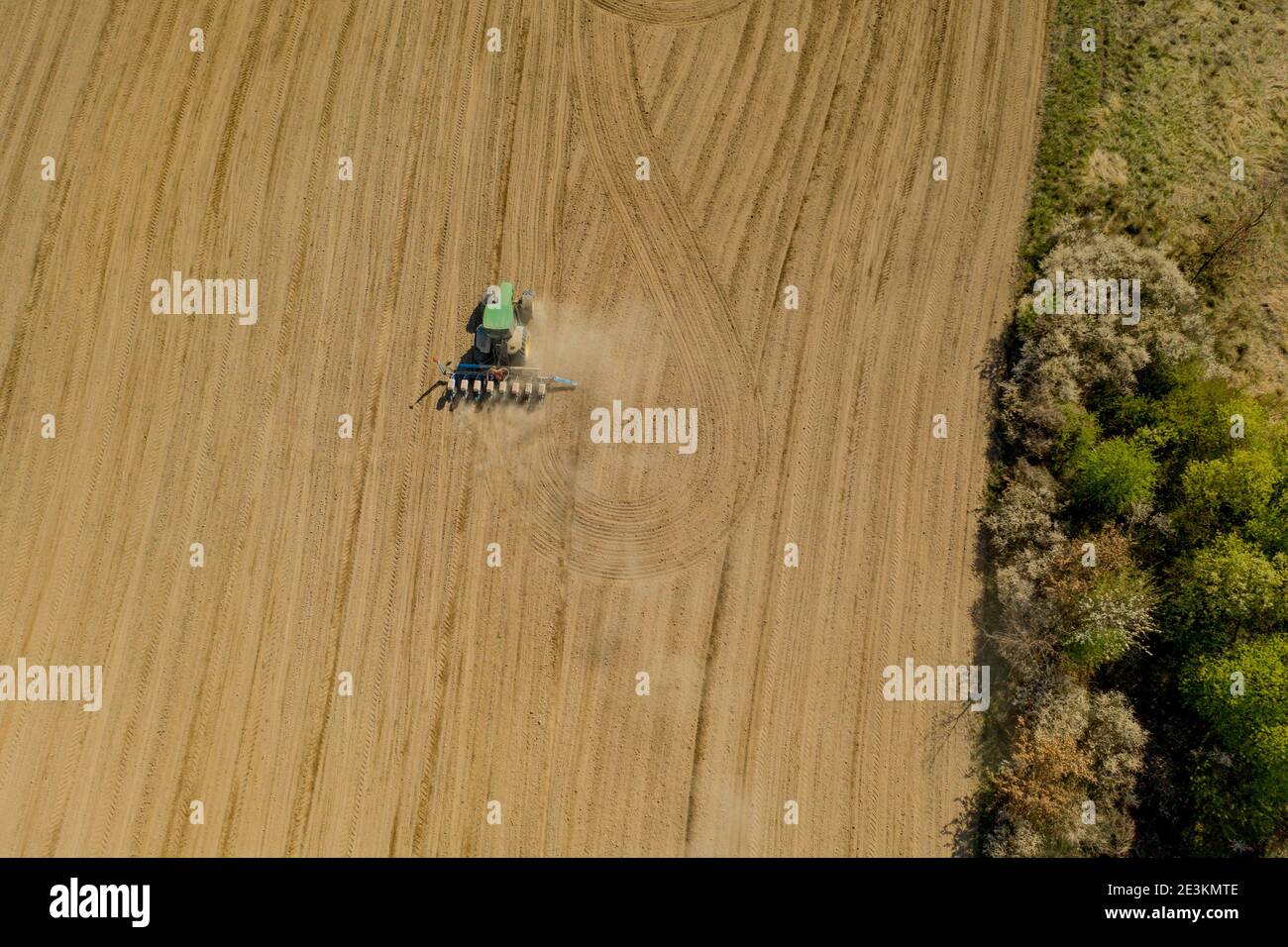 Aerial view large tractor cultivating a dry field. Top down aerial view ...