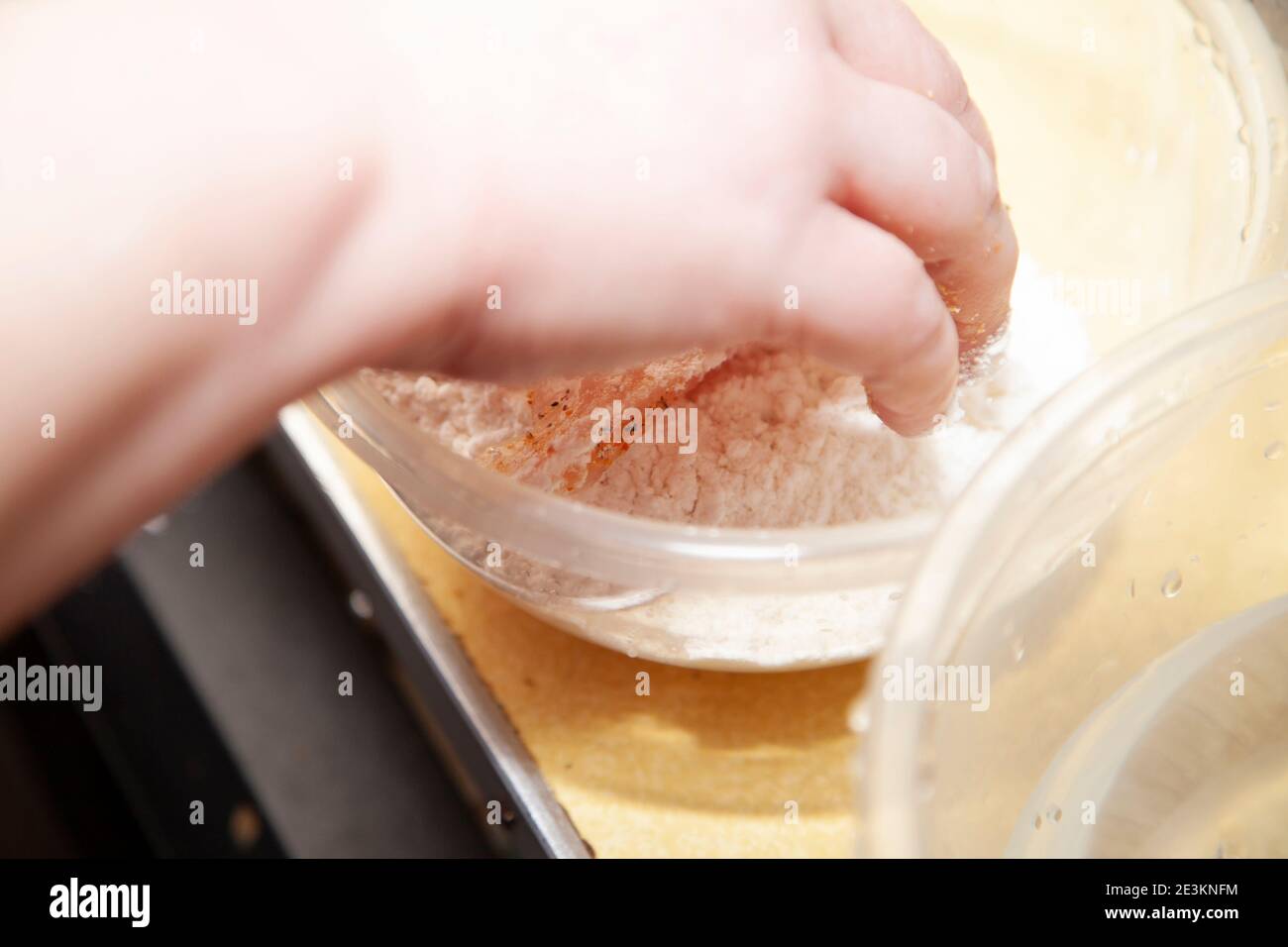 Woman's hand rolling a raw, seasoned chicken tender in flour Stock ...