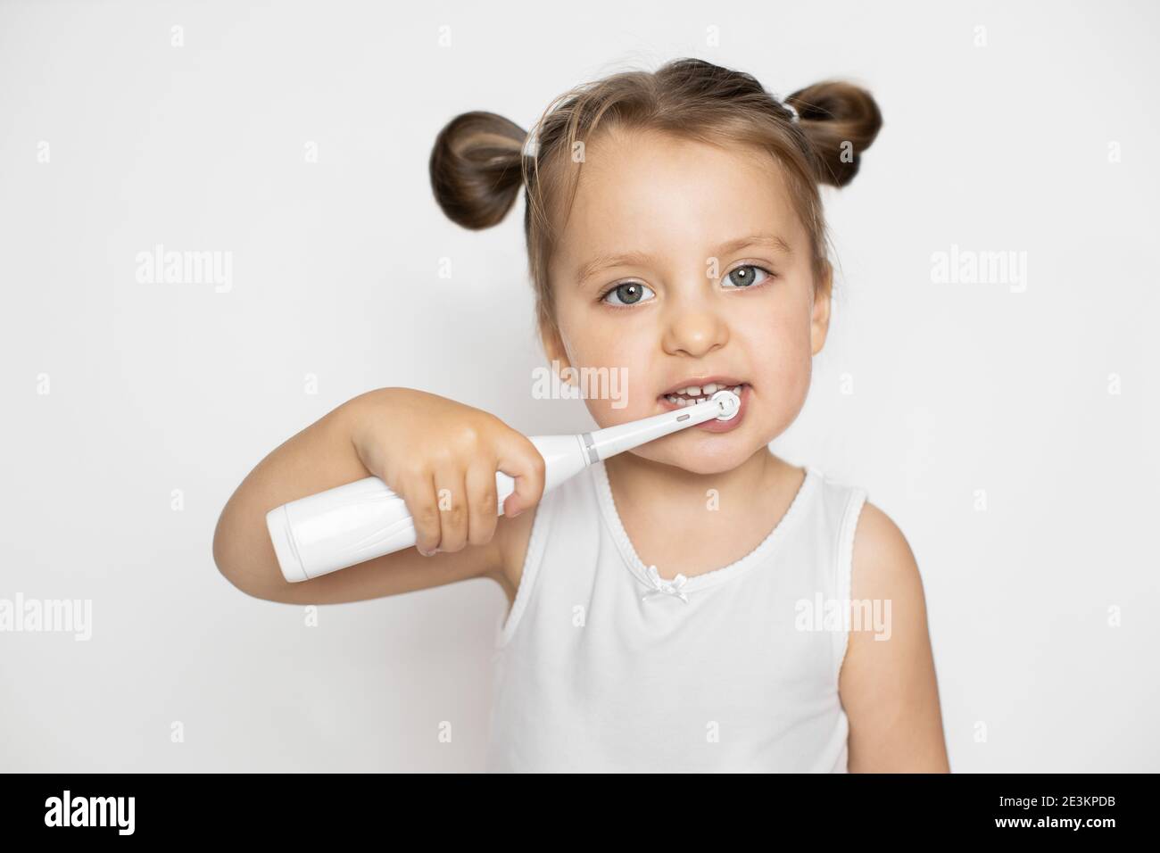 Little cute blond girl brushing her teeth with electric toothbrush ...